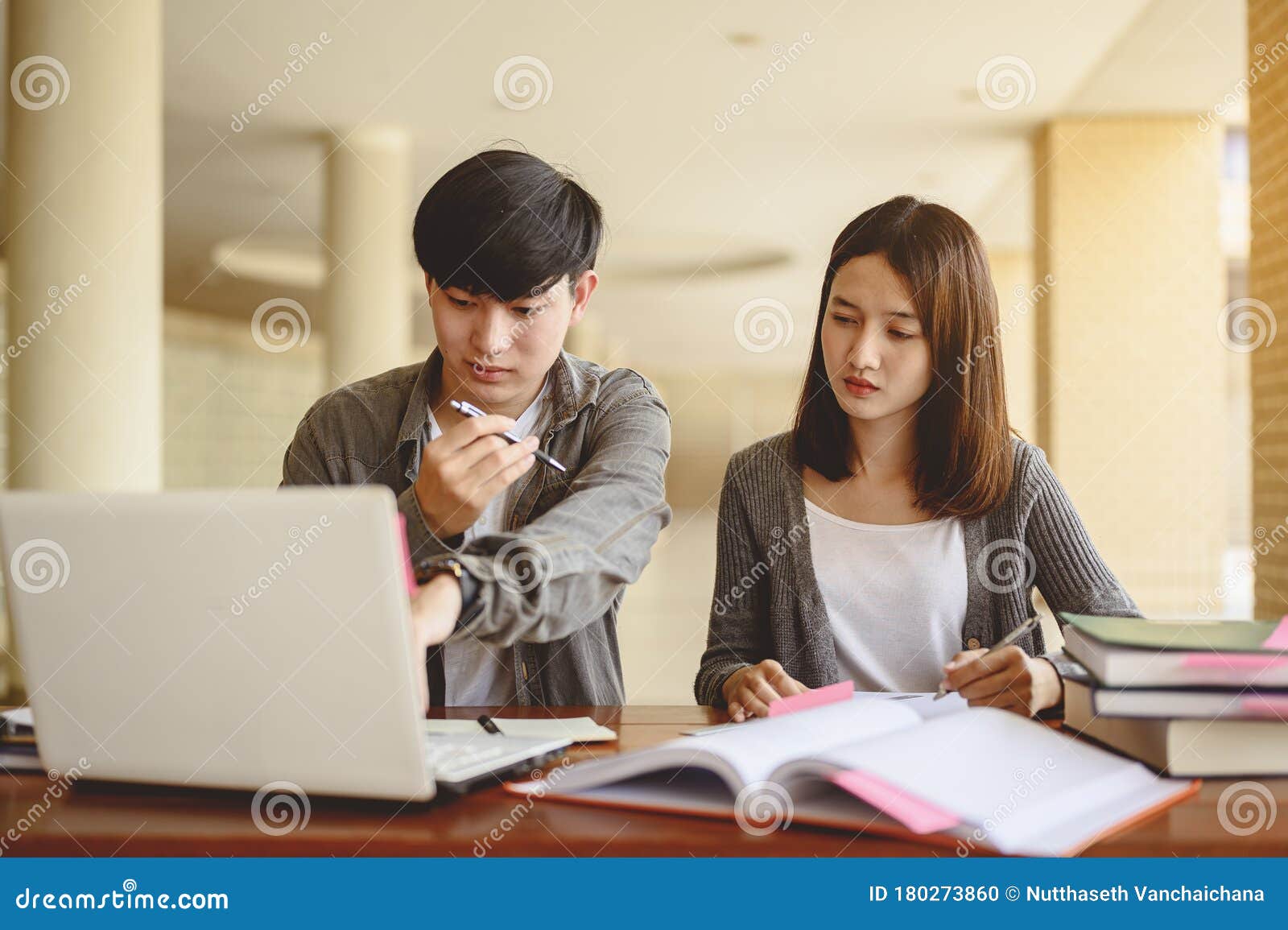 Two Students are Sitting at Table Reading Books To Education. Study for ...