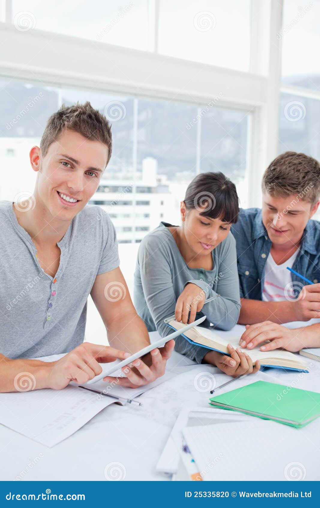 Two Students Use a Book while the Student Using a Tablet Looks a Stock ...