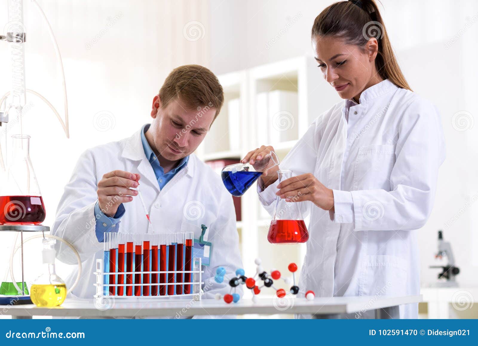 Two Young Students Working at Lab and Taking Notes Off Chamical Stock ...