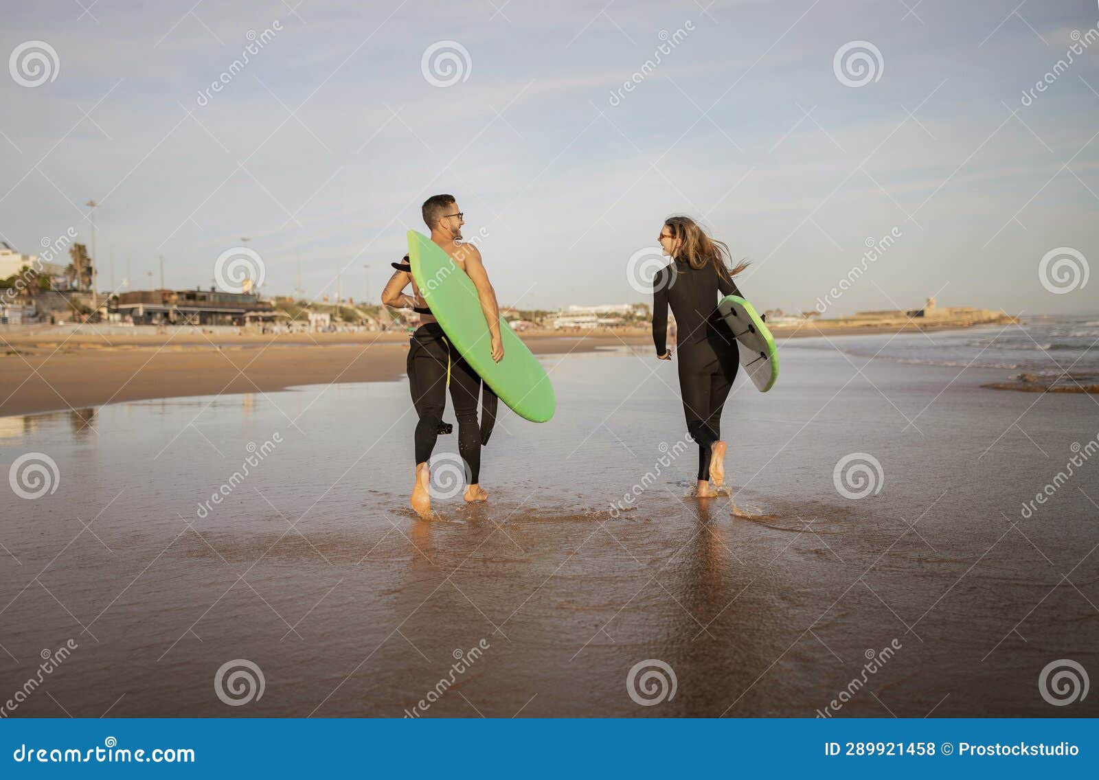 Two Surfers Man And Woman Walking With Surfboards Along The Beach Stock