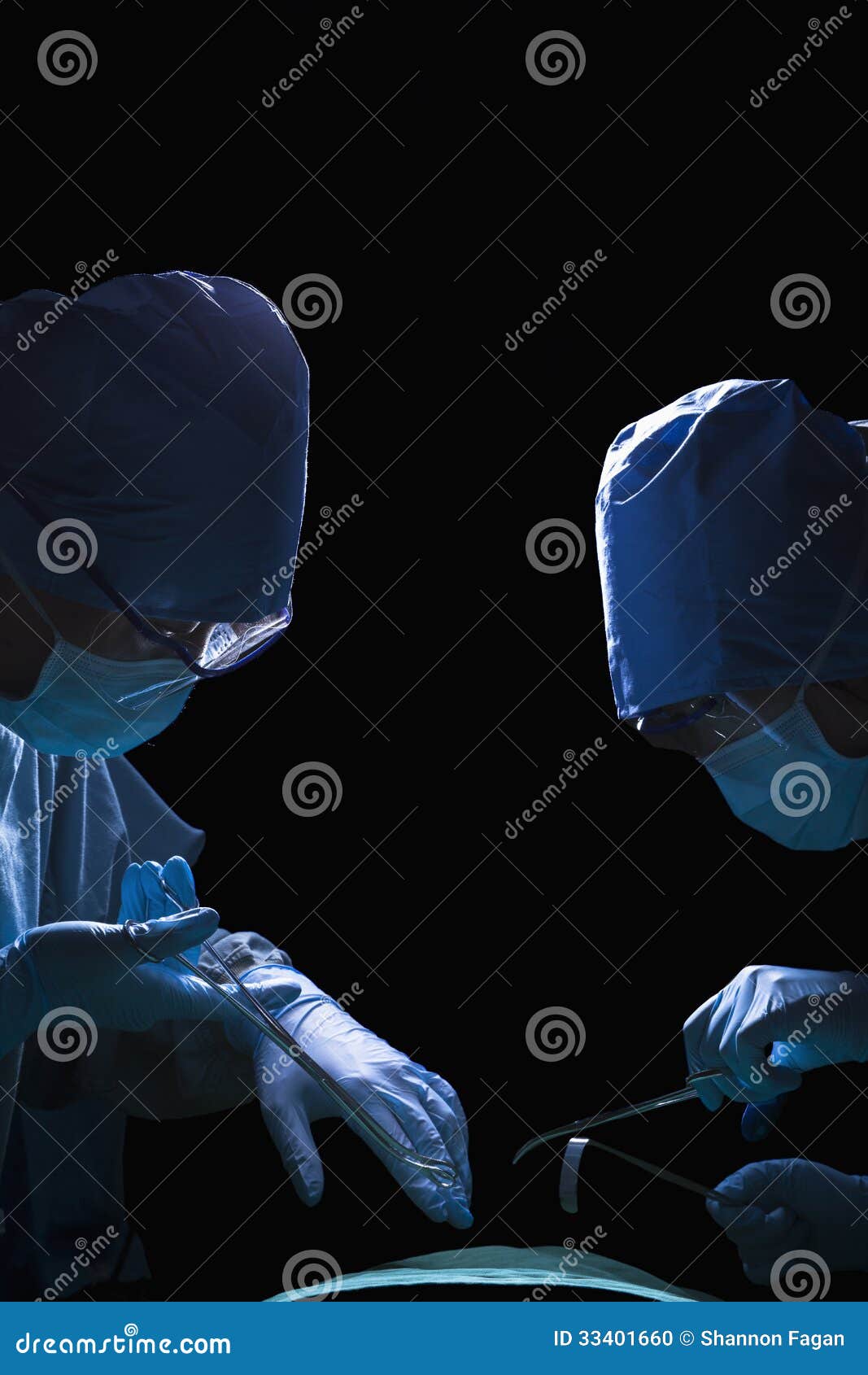Two Surgeons Looking Down, Working, and Holding Surgical Equipment with ...