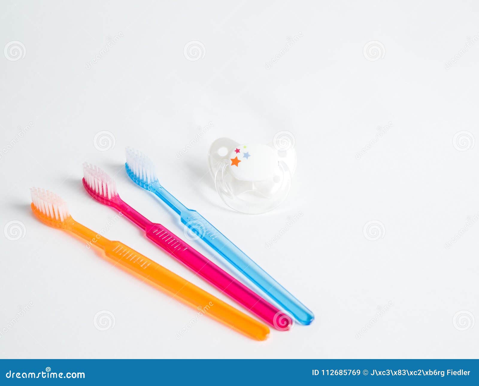 Three Toothbrushes in a Glass with Pacifier on a White Background Stock ...