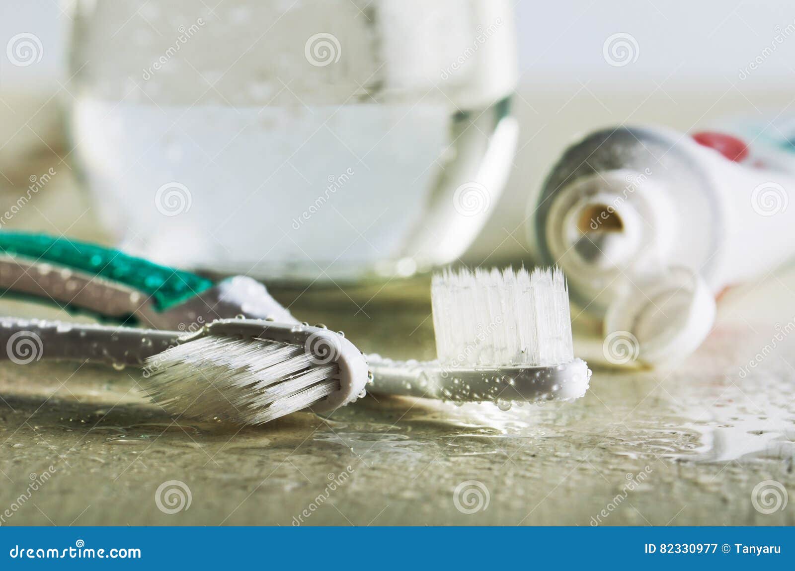 Two Toothbrushes, Toothpaste and a Glass of Water on a Wet Table Stock ...