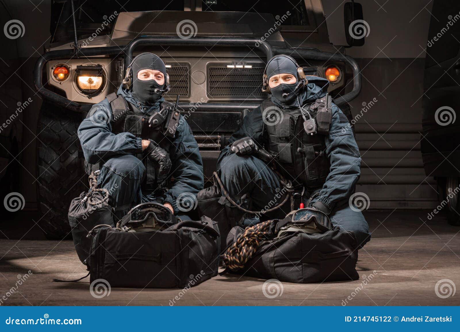 Two Uniformed Commandos Sit in a Hangar with a Military Truck in the ...