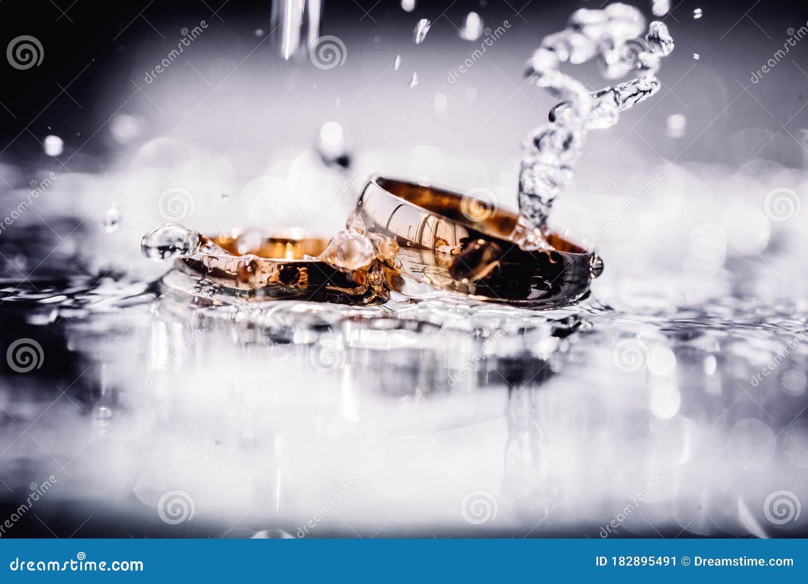 Two Wedding Rings in Water Splashes Laying on Flat Surface Stock Image ...