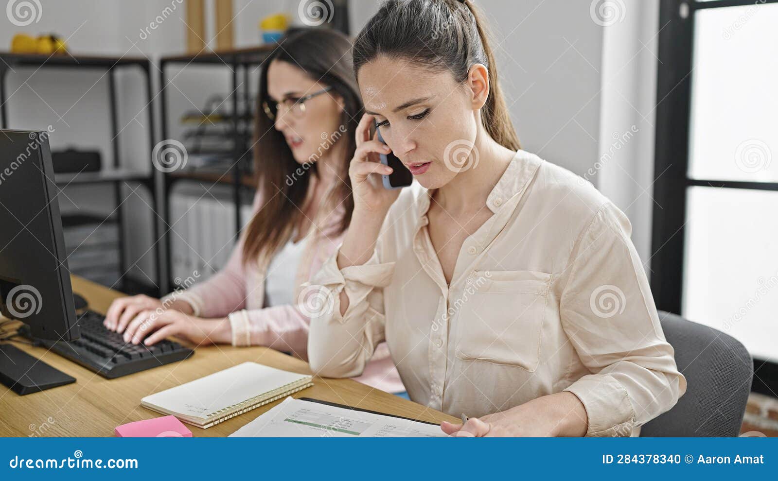 Two Women Business Workers Sitting on Table Working at Office Stock ...