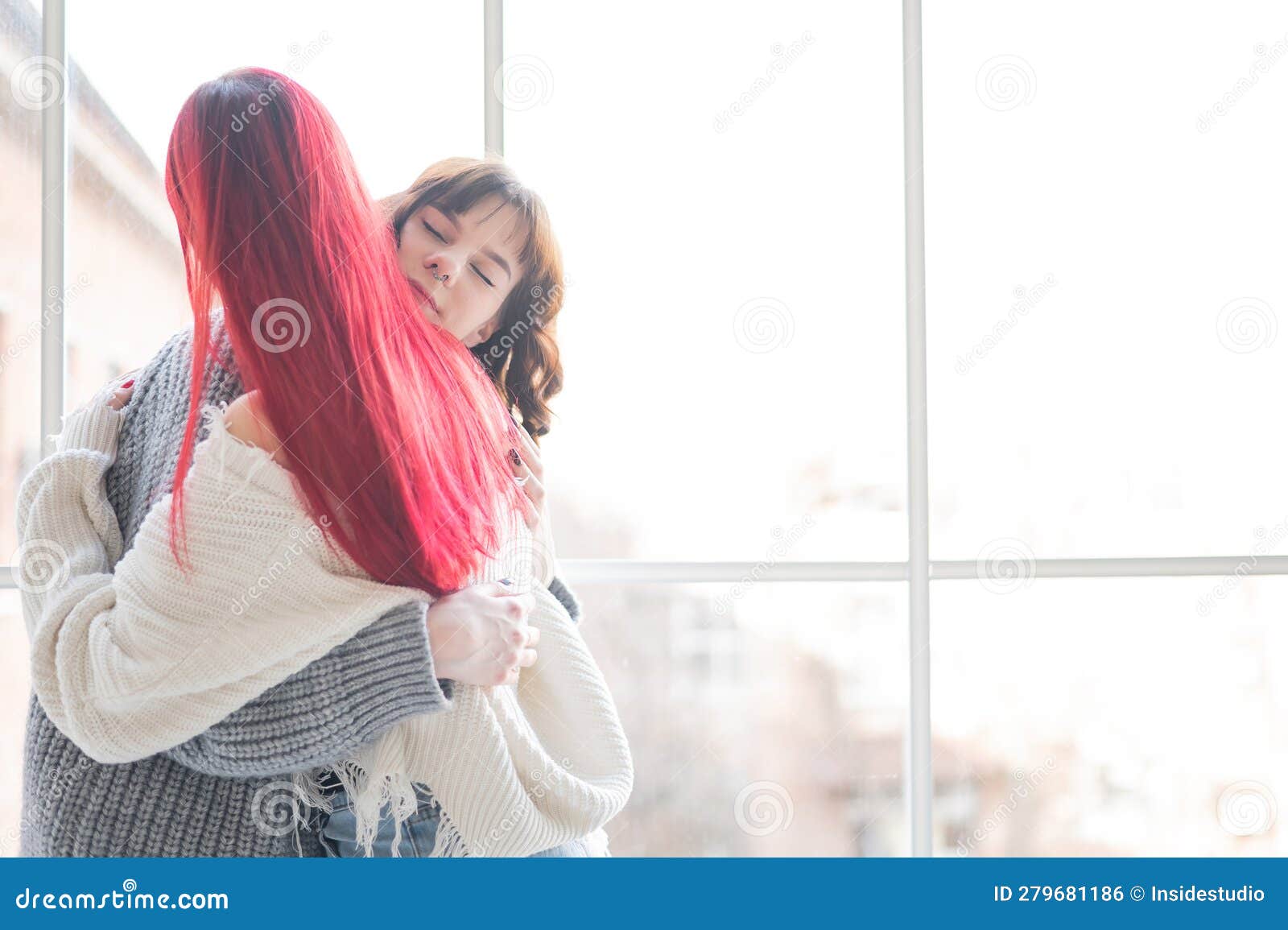 Two Women Dressed In Sweaters Sit By The Window And Gently Hug Lesbian