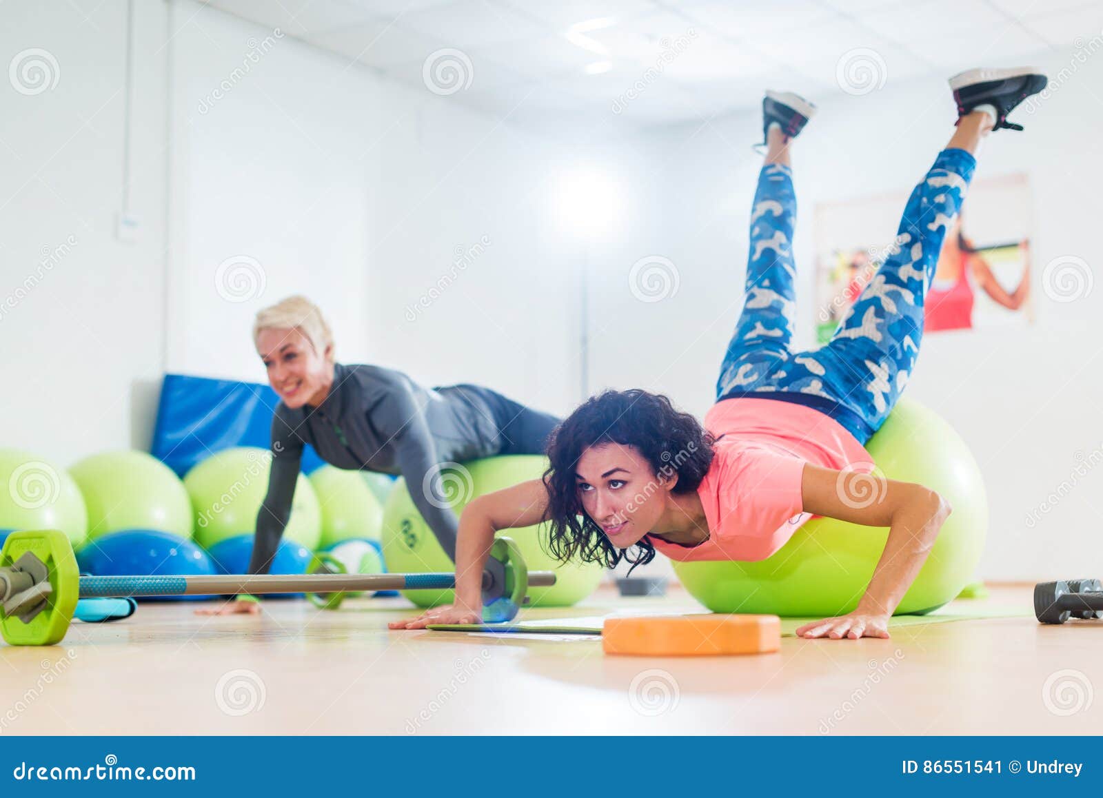 Two Women Exercising with Stability Balls Doing Push-ups in a Gym Class ...