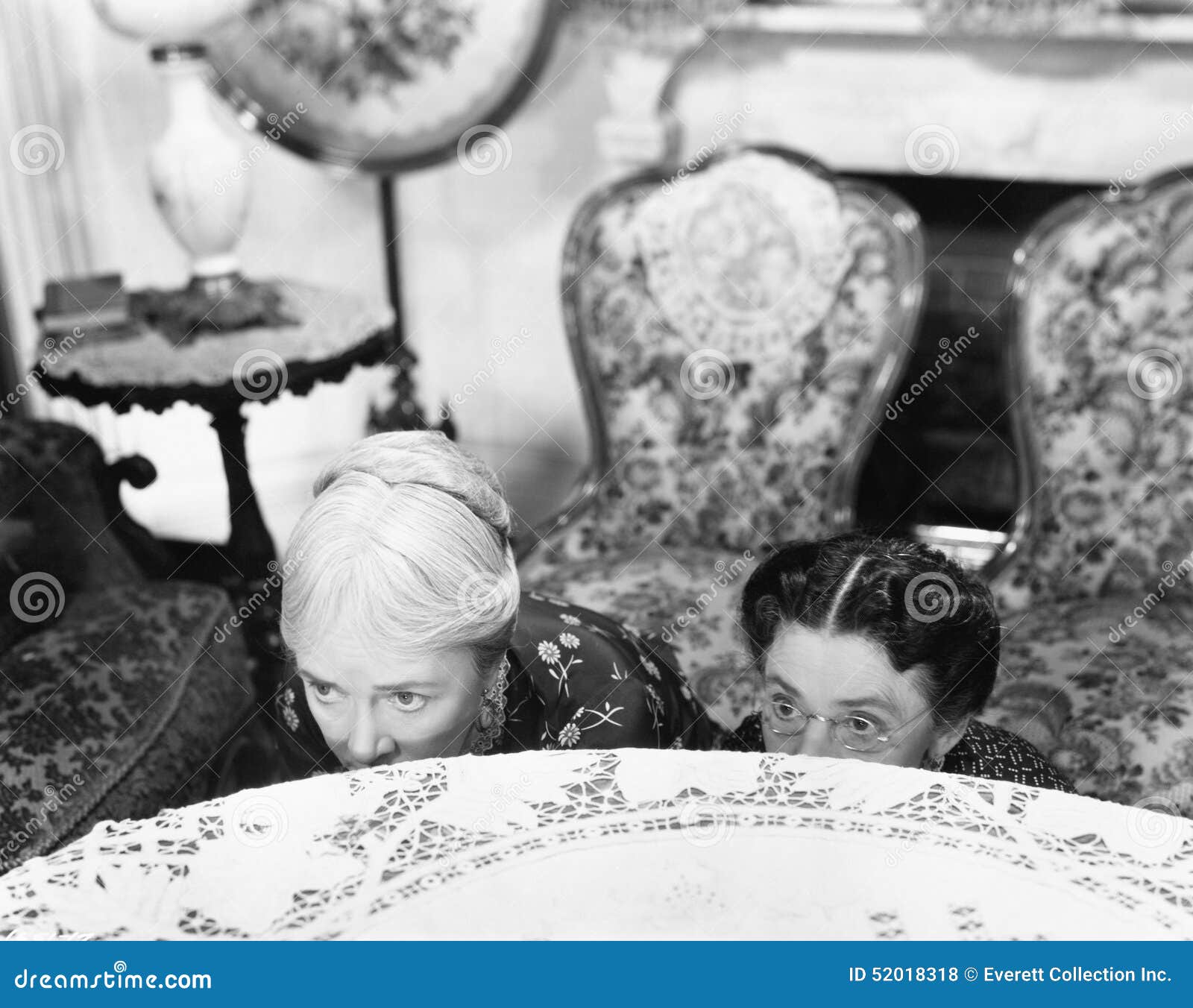 Two Women Hiding Behind a Table and Looking Over the Edge Stock Photo ...