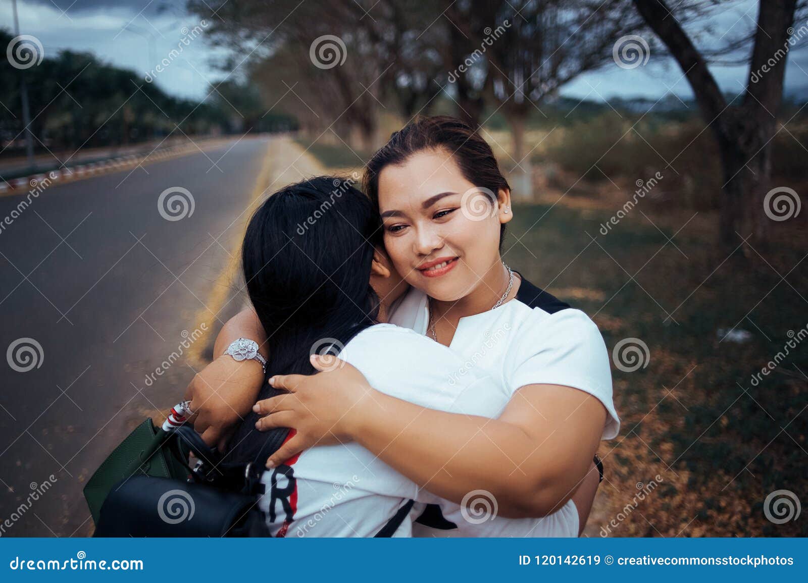 Two Women Hugging Each Other Standing On Pathway Of The Road Picture ...