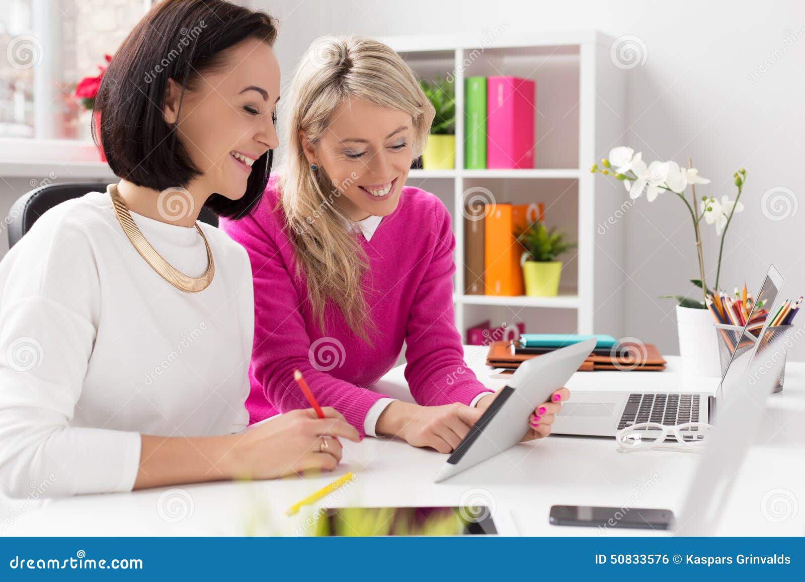 Two Women Looking at Tablet Computer while Working in Office Stock ...
