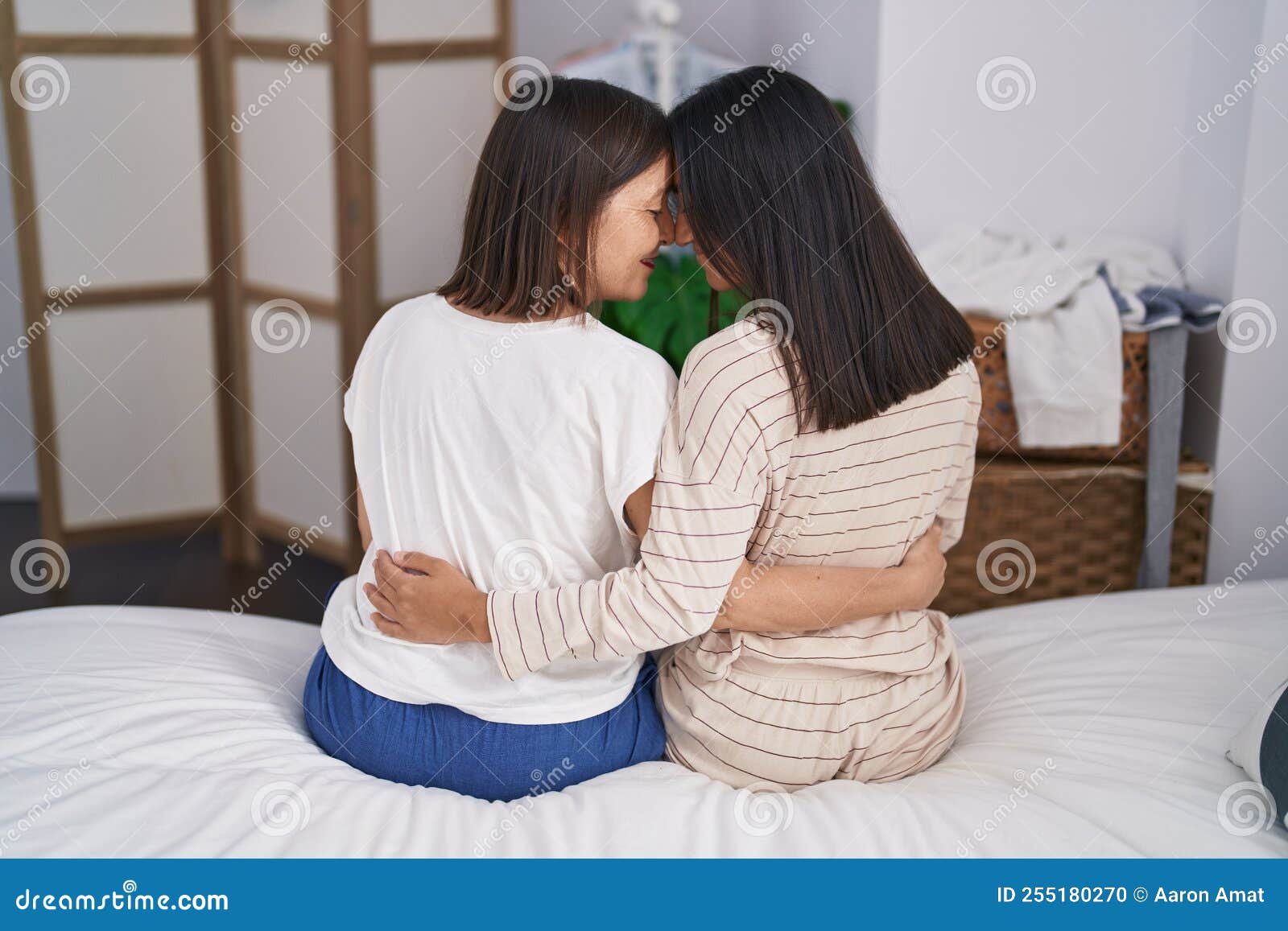 Two Women Mother And Daughter Hugging Each Other Sitting On Bed At