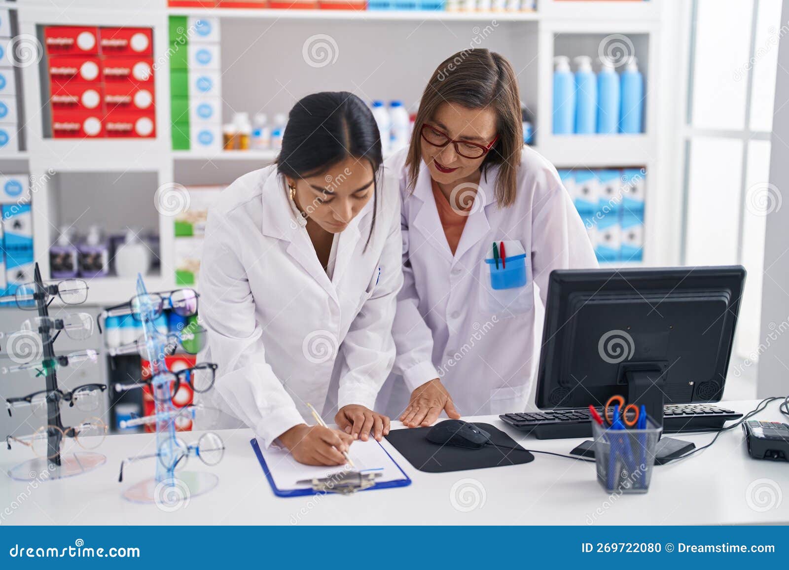 Two Women Pharmacist Smiling Confident Writing on Document at Pharmacy ...