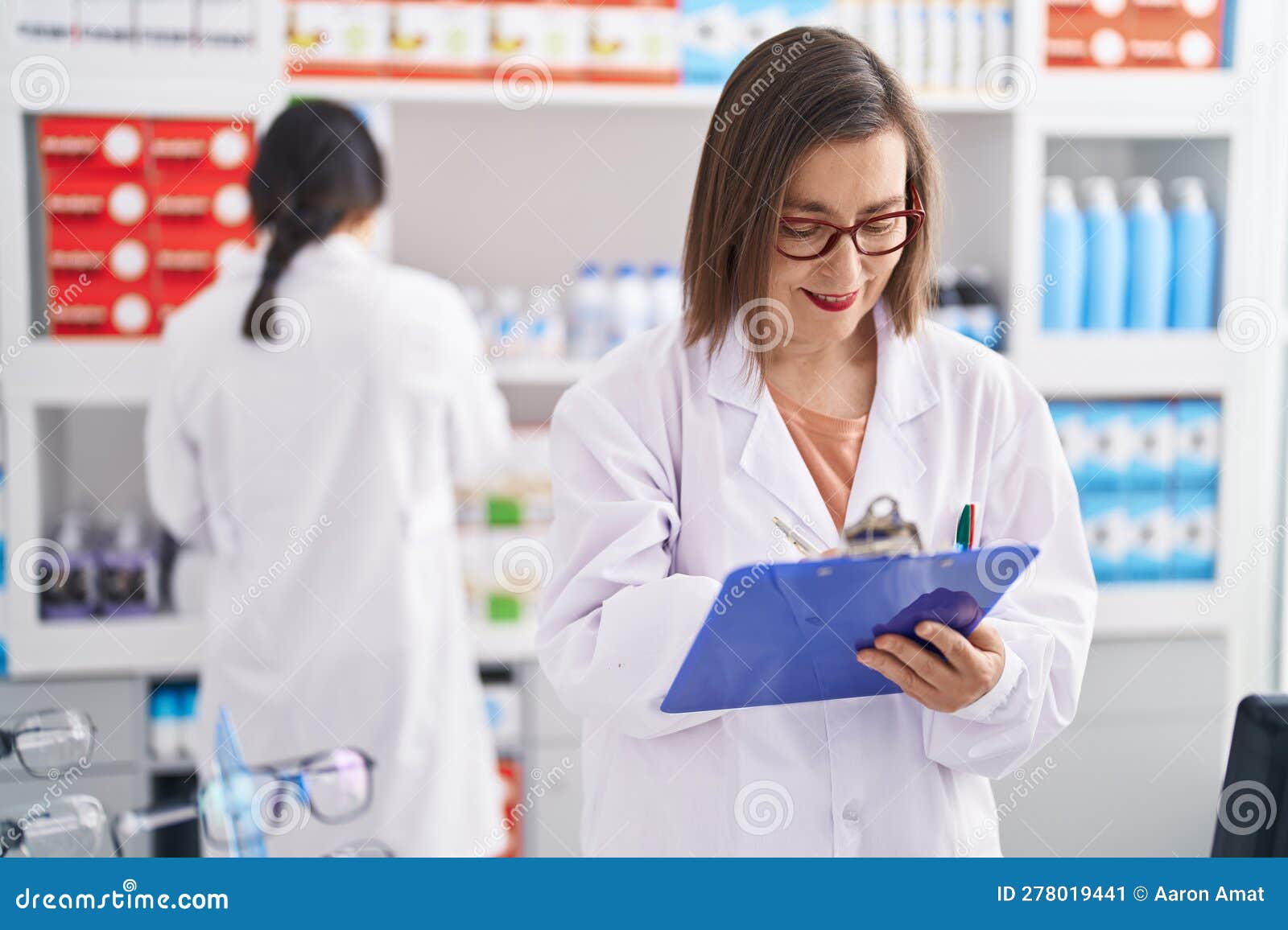 Two Women Pharmacist Smiling Confident Writing on Document at Pharmacy ...