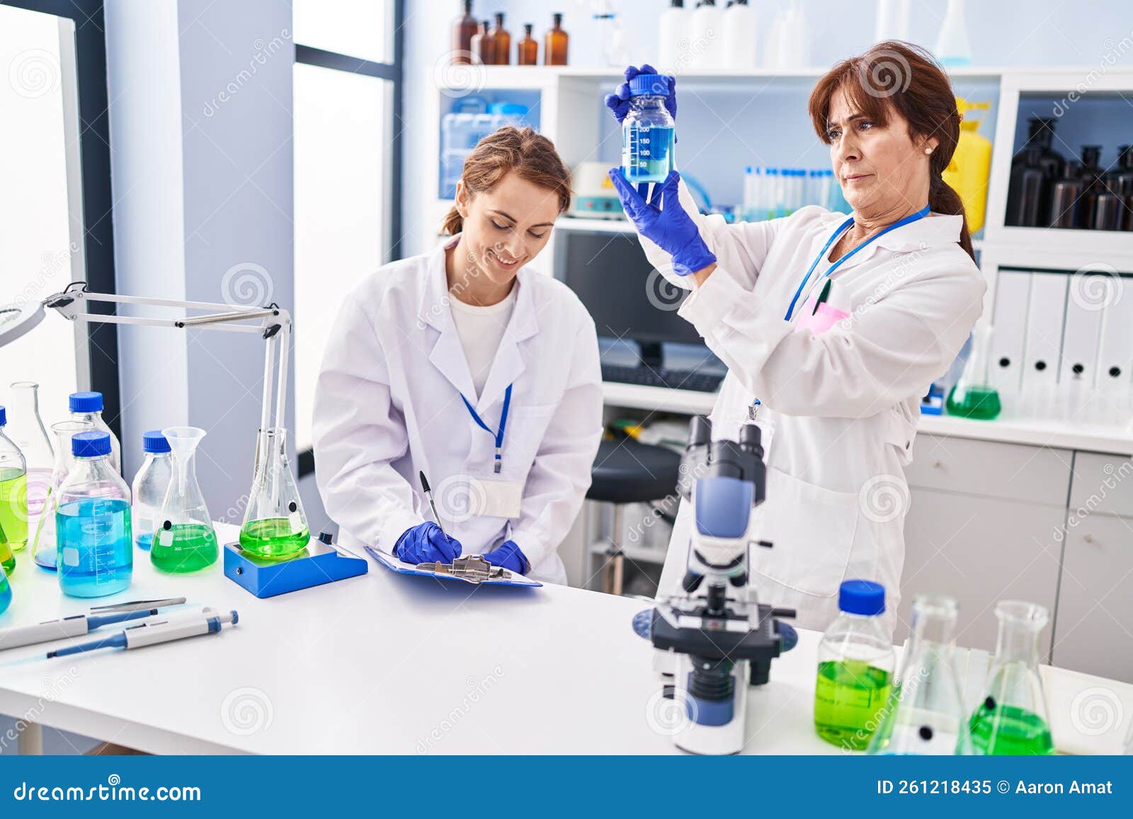 Two Women Scientists Holding Test Tube Writing on Document at ...