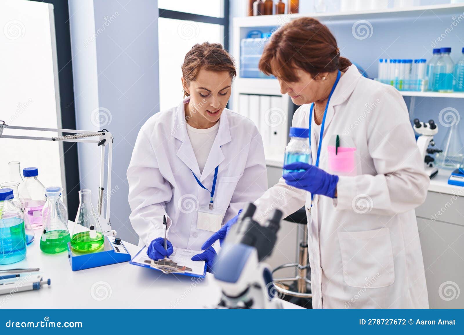 Two Women Scientists Holding Test Tube Writing on Document at ...
