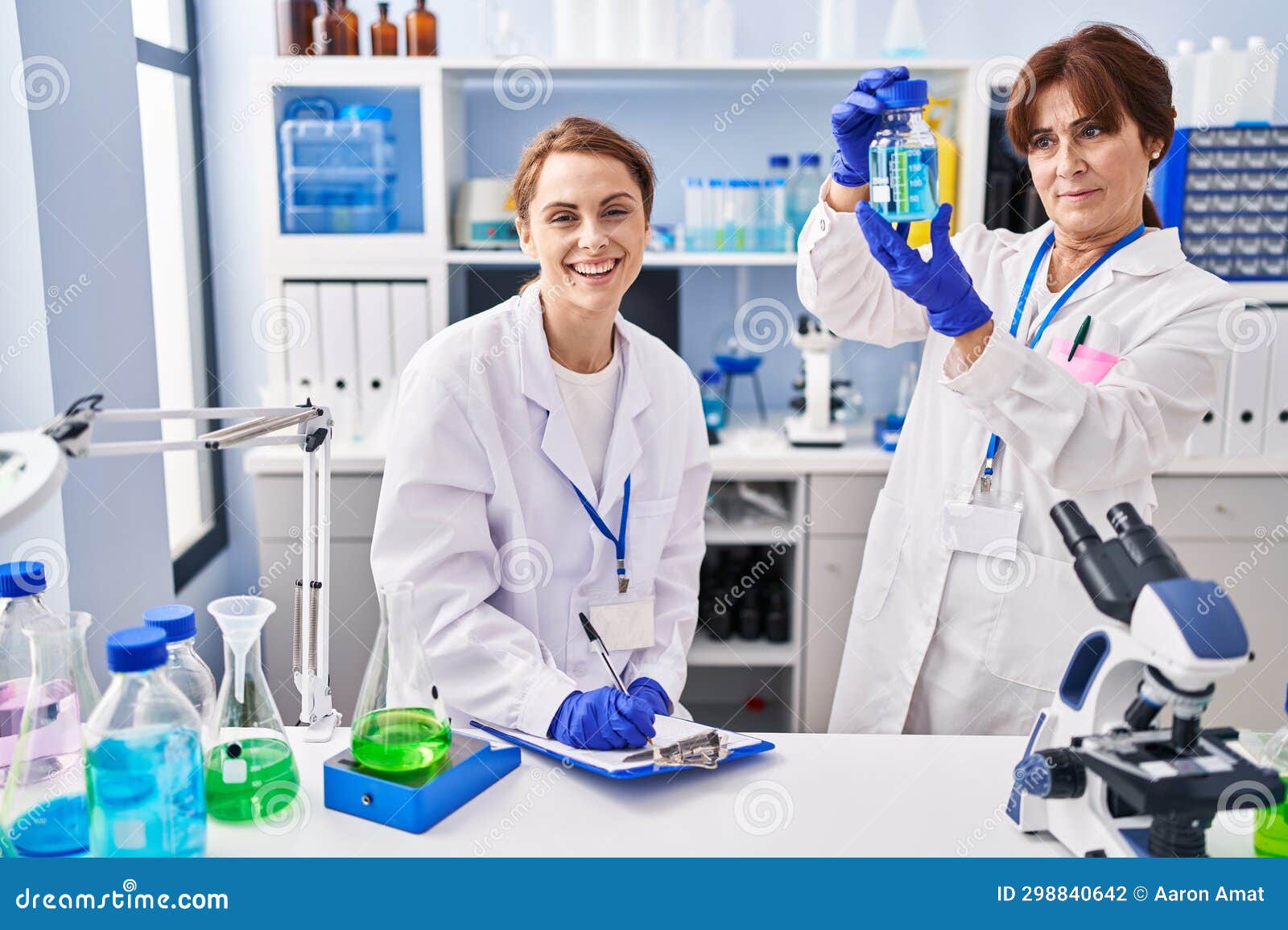 Two Women Scientists Holding Test Tube Writing on Document at ...