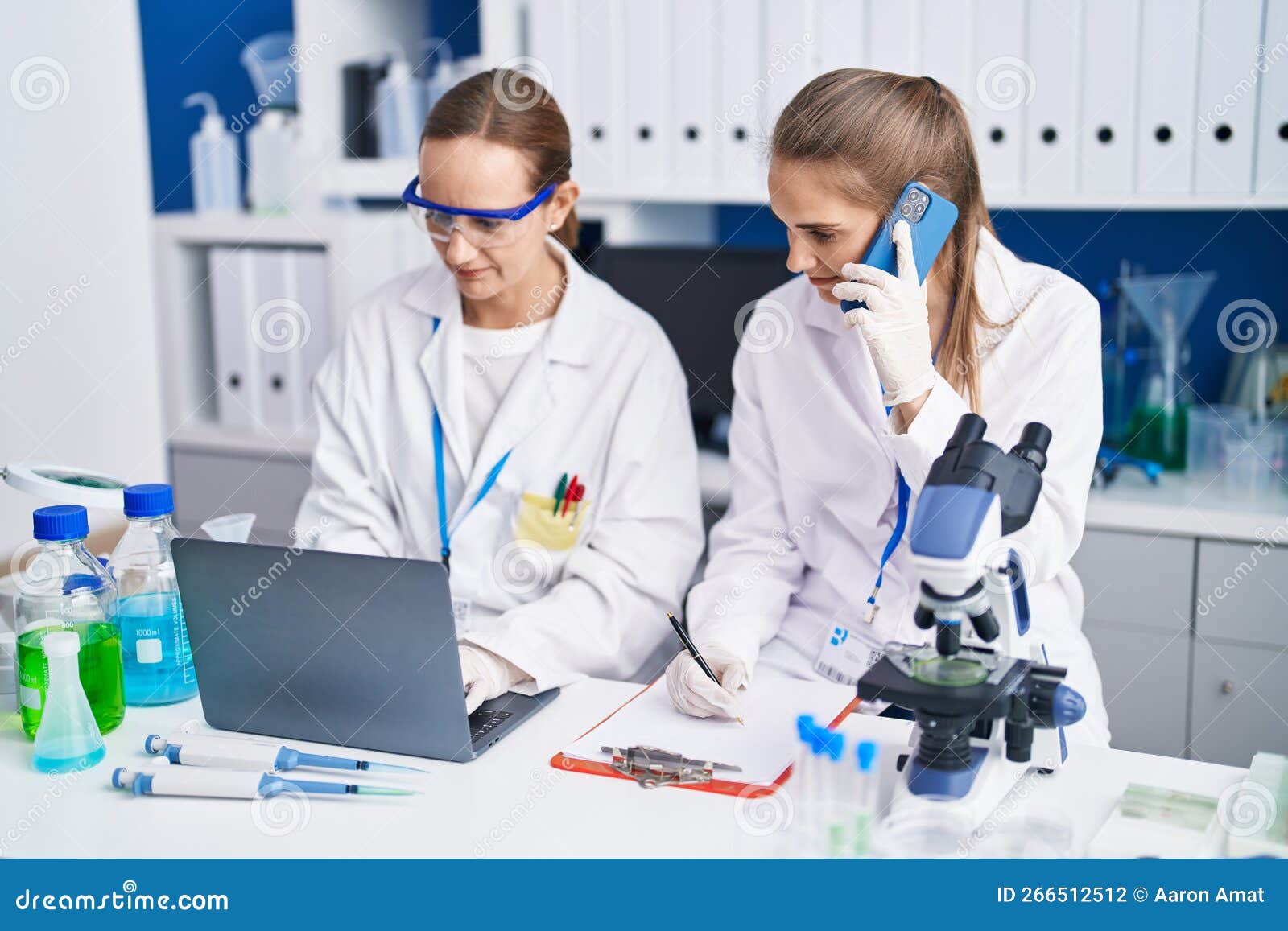 Two Women Scientists Talking on the Smartphone Working at Laboratory ...