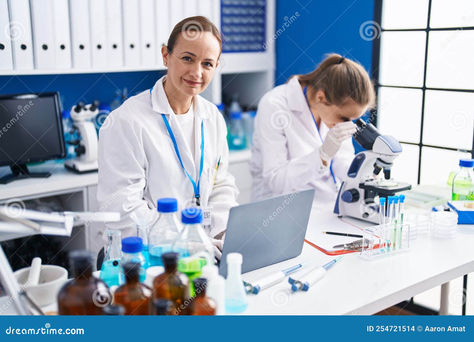 Two Women Scientists Using Microscope and Laptop at Laboratory Stock ...