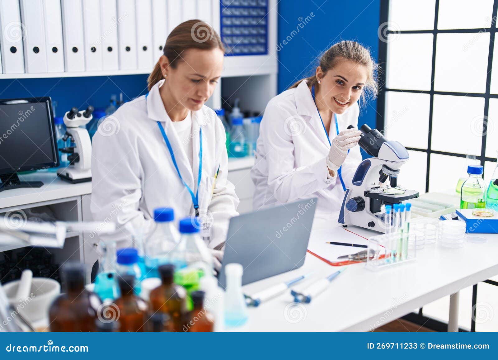 Two Women Scientists Using Microscope and Laptop at Laboratory Stock ...