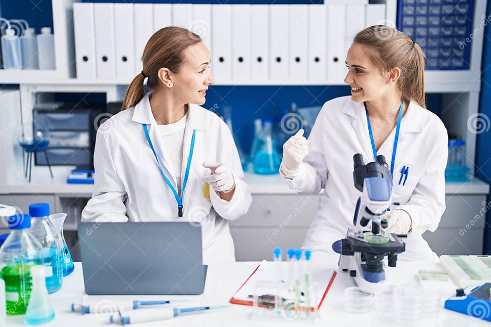 Two Women Scientists Using Microscope and Laptop at Laboratory Stock ...