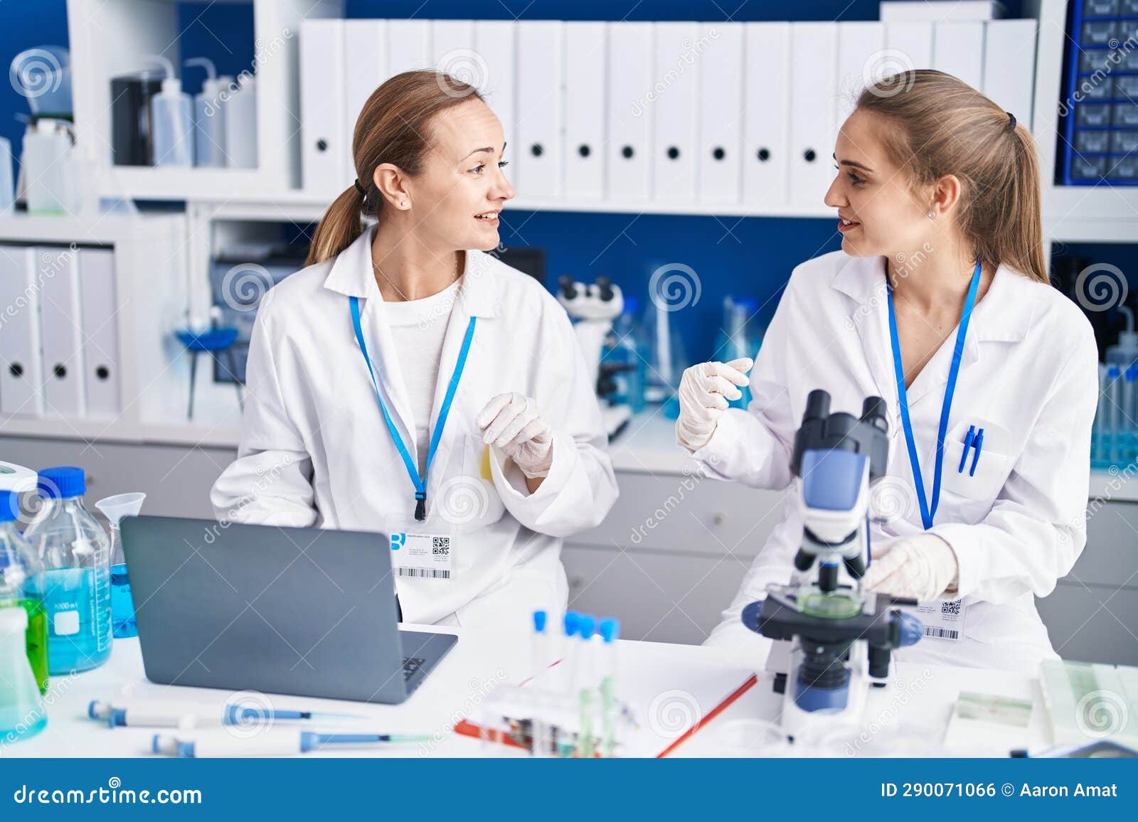 Two Women Scientists Using Microscope and Laptop at Laboratory Stock ...