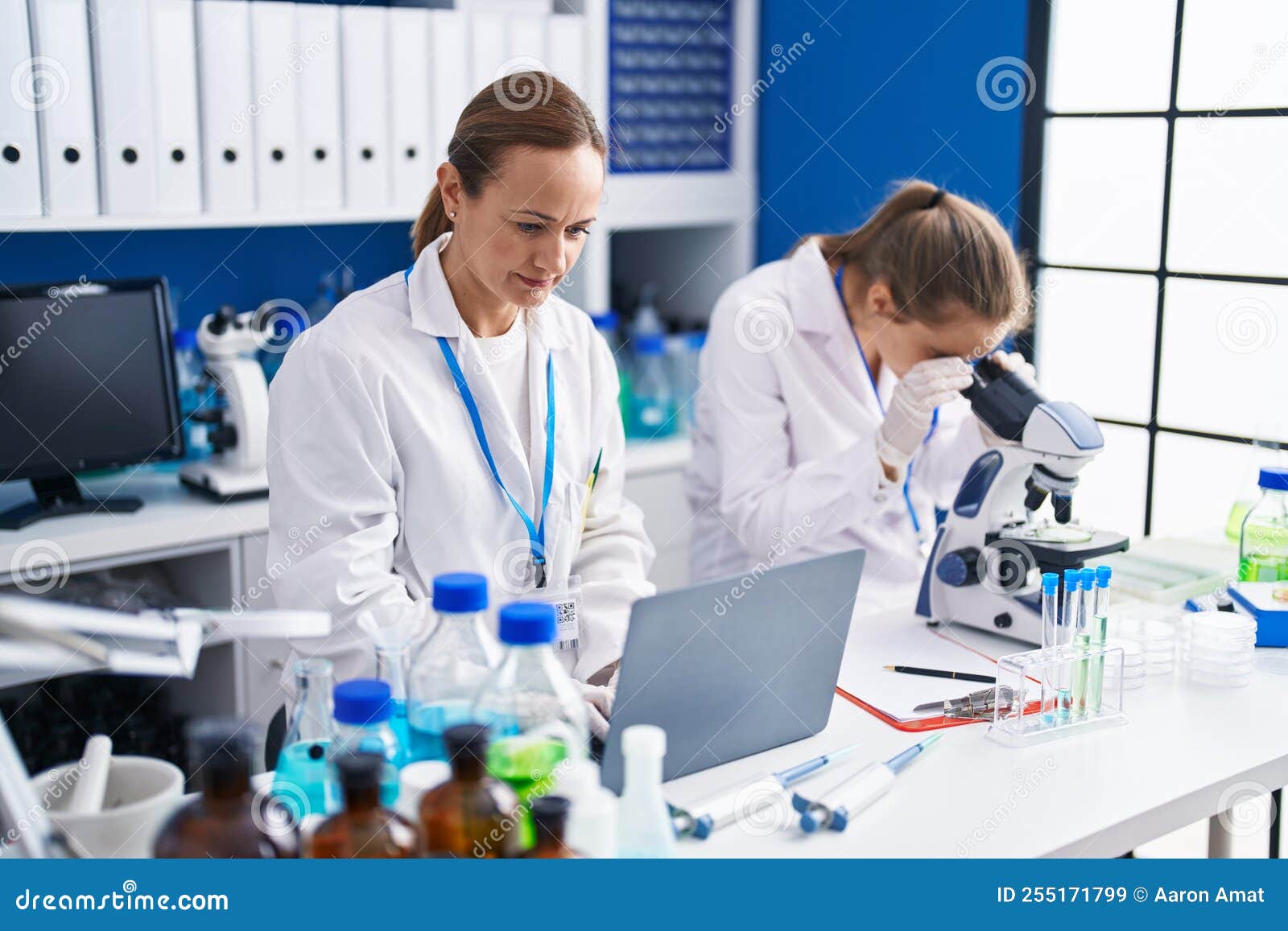 Two Women Scientists Using Microscope and Laptop at Laboratory Stock ... Two Women Scientists Using Microscope and Laptop at Laboratory Stock ...