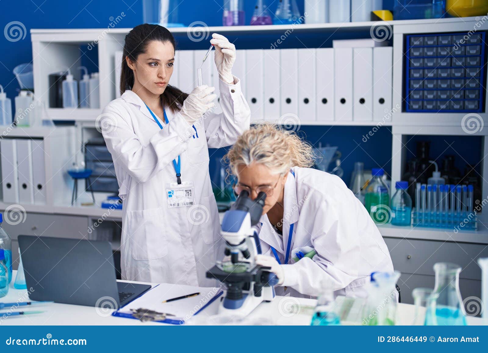 Two Women Scientists Using Microscope Measuring Liquid at Laboratory ...