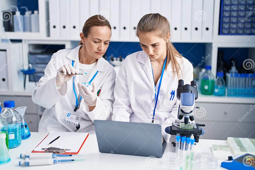 Two Women Scientists Using Microscope and Write on Document at ...