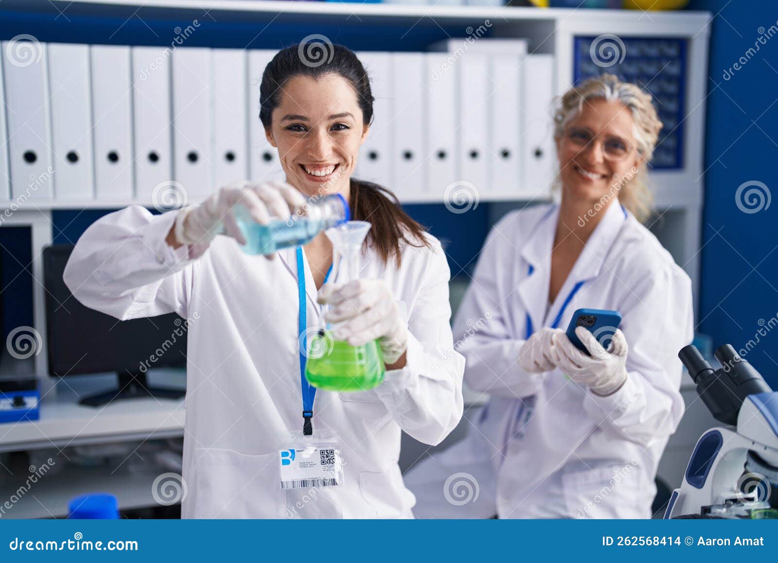 Two Women Scientists Using Smartphone and Measuring Liquid at ...
