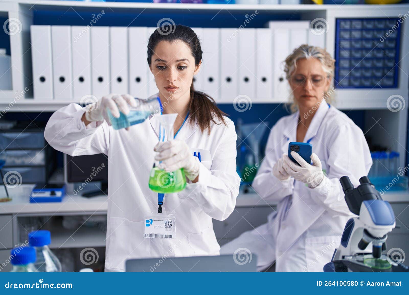 Two Women Scientists Using Smartphone and Measuring Liquid at ...