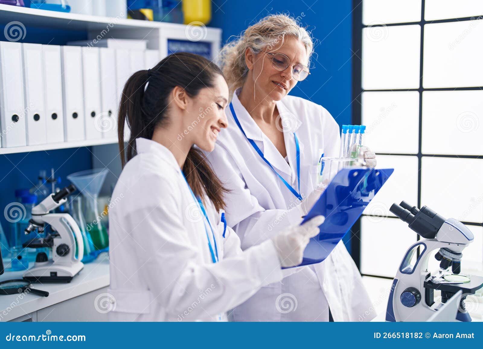 Two Women Scientists Writing on Document Holding Test Tubes at ...