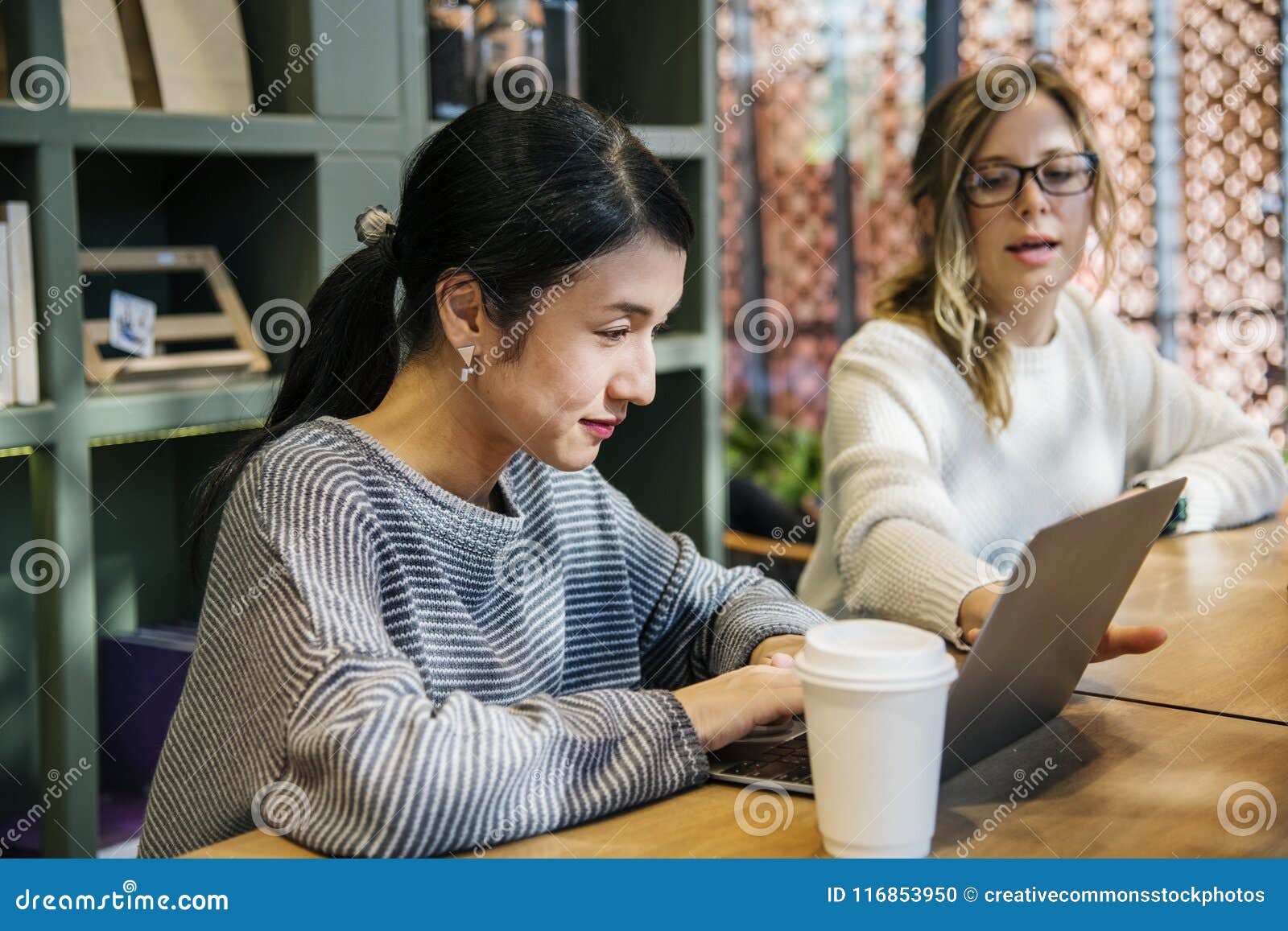 Two Women Sitting In Front Of Brown Wooden Table Picture. Image: 116853950