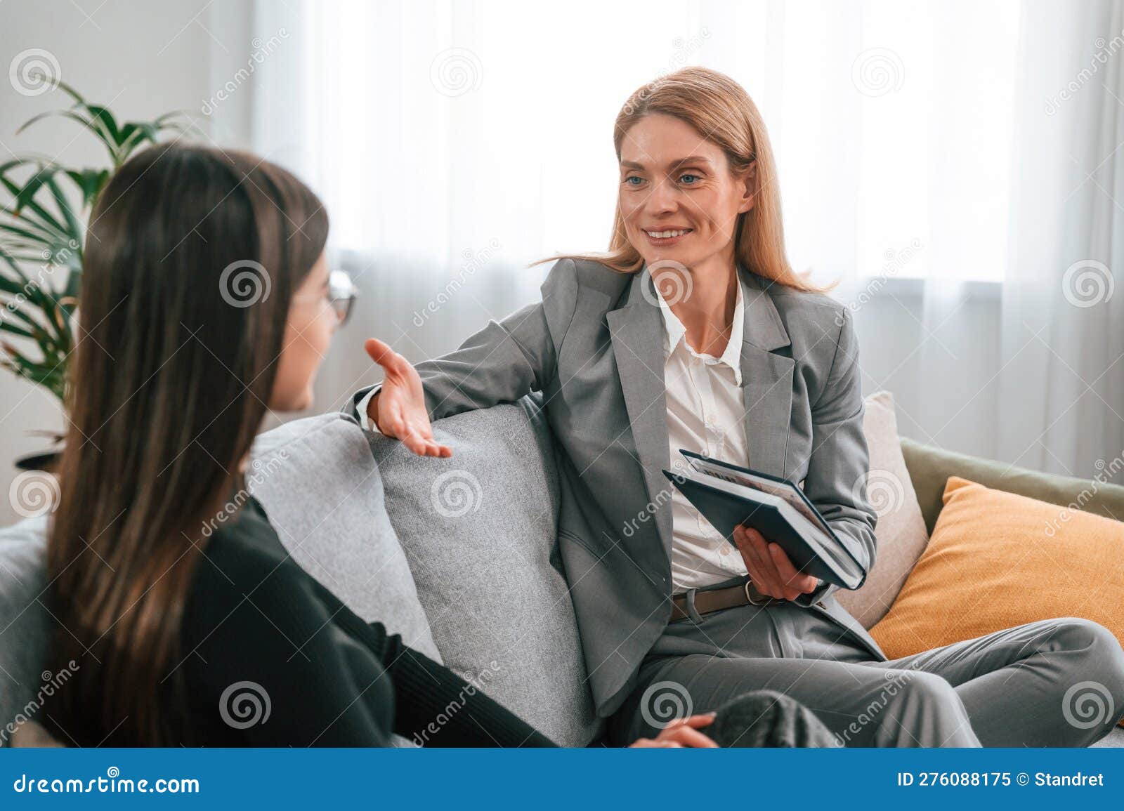 Two Women is Sitting on the Sofa and Talking. Casual and Formal Clothes ...