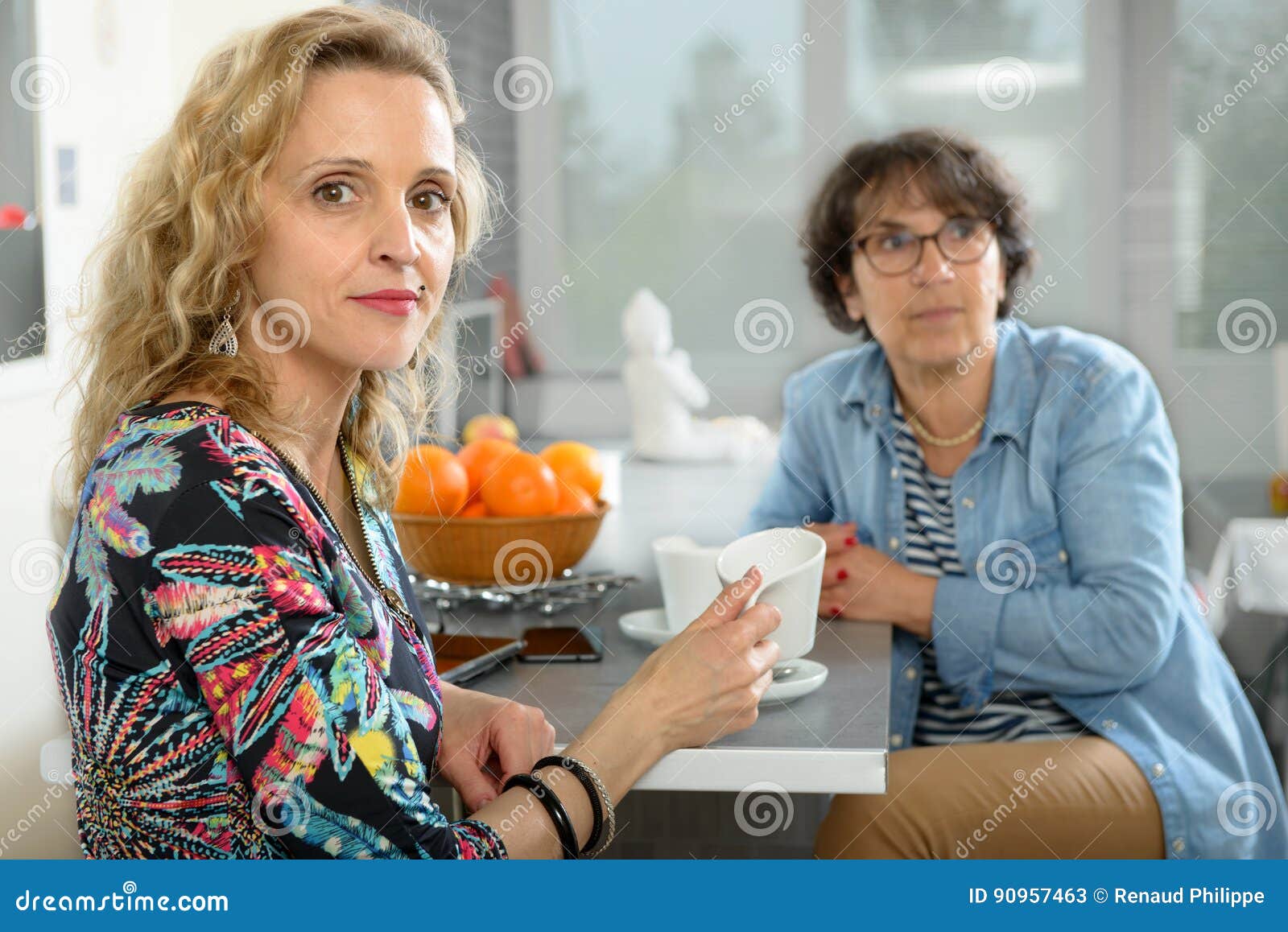Two Women Sitting at Table in Kitchen and Drinking Coffee. Stock Image ...