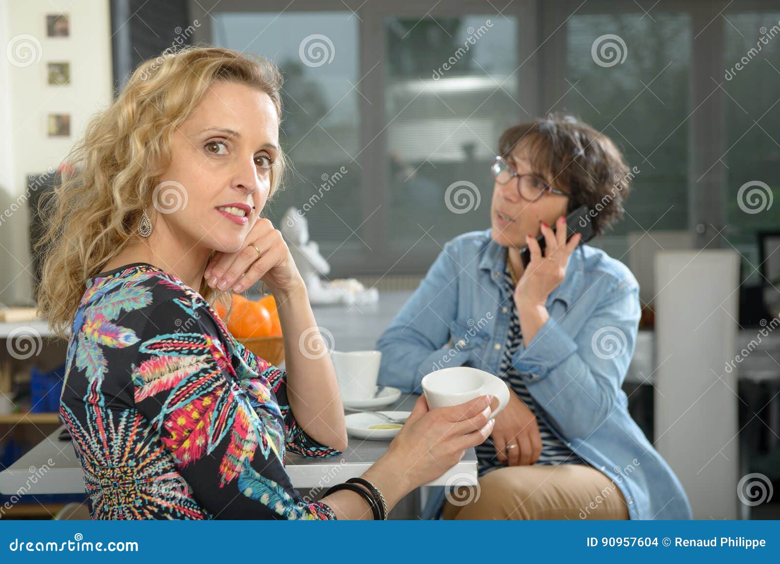 Two Women Sitting at Table in Kitchen and Drinking Coffee. Stock Photo ...