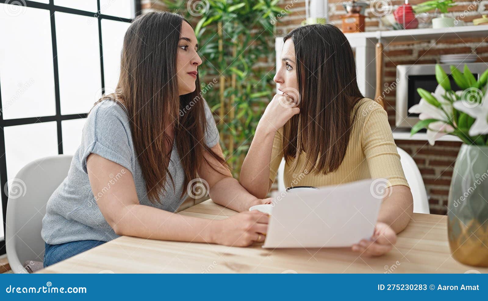 Two Women Sitting on Table Reading Paper at Dinning Room Stock Image ...