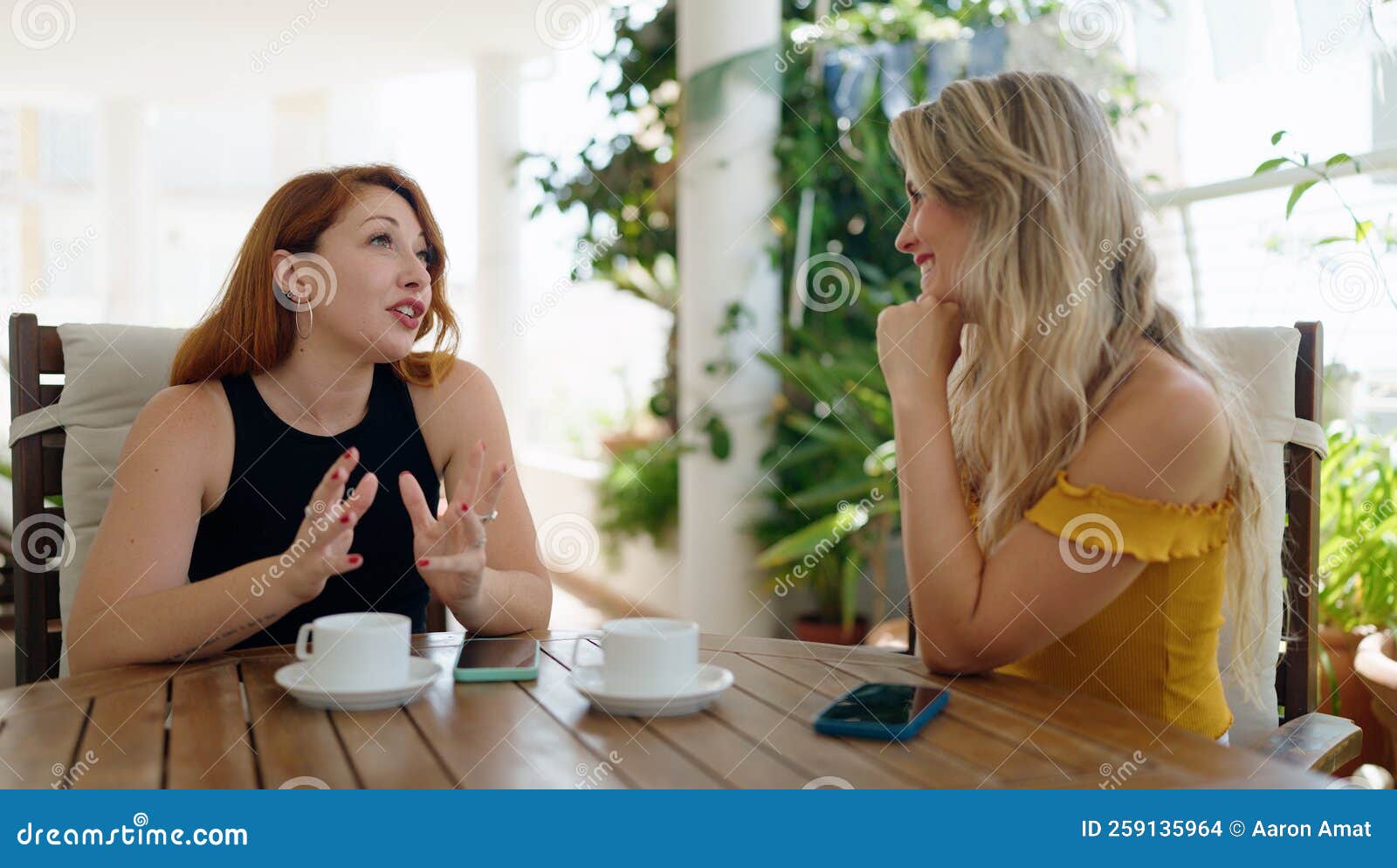 Two Women Sitting on Table Speaking and Drinking Coffee at Home Terrace ...