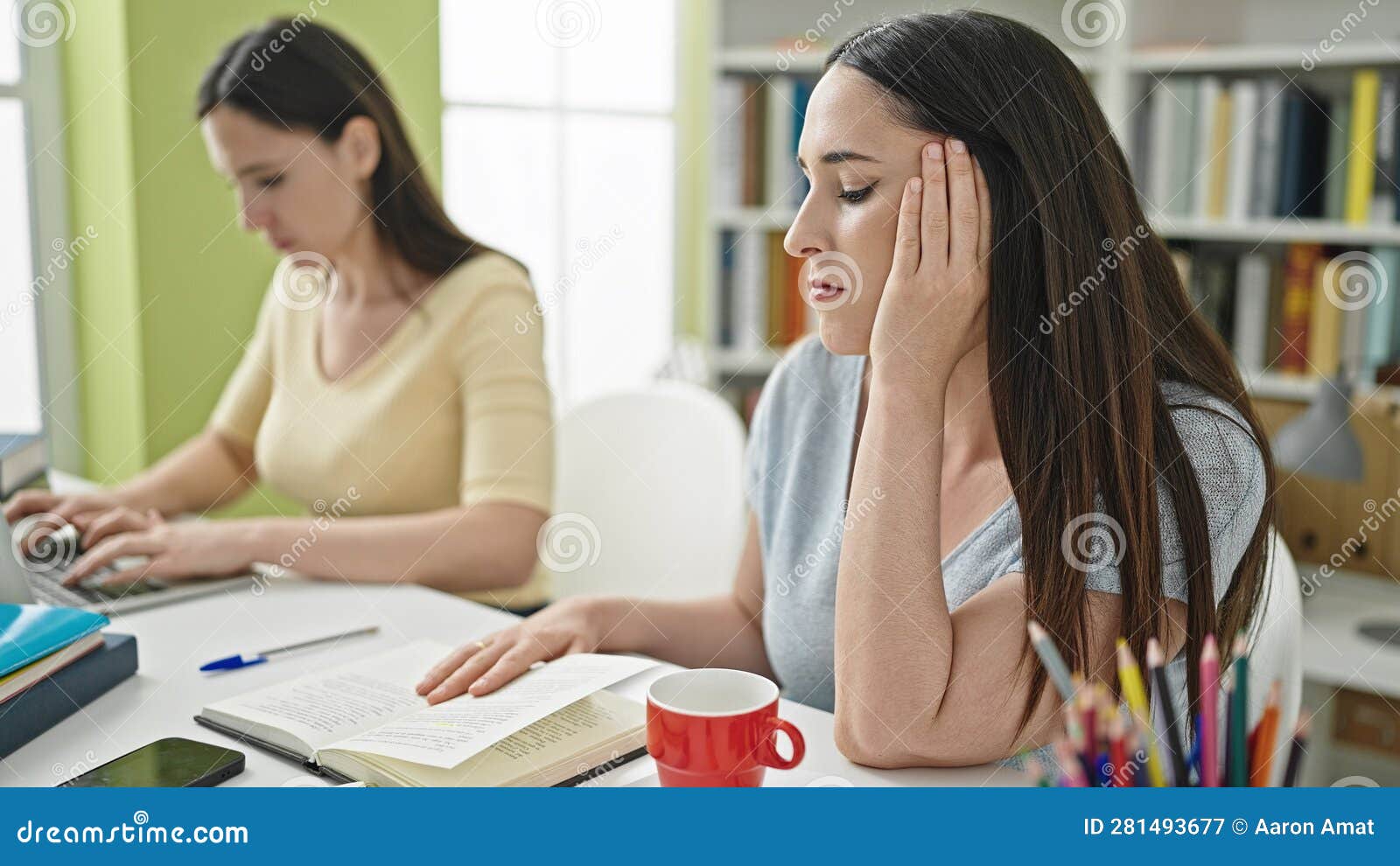 Two Women Sitting on Table Studying with Boring Expression at Library ...