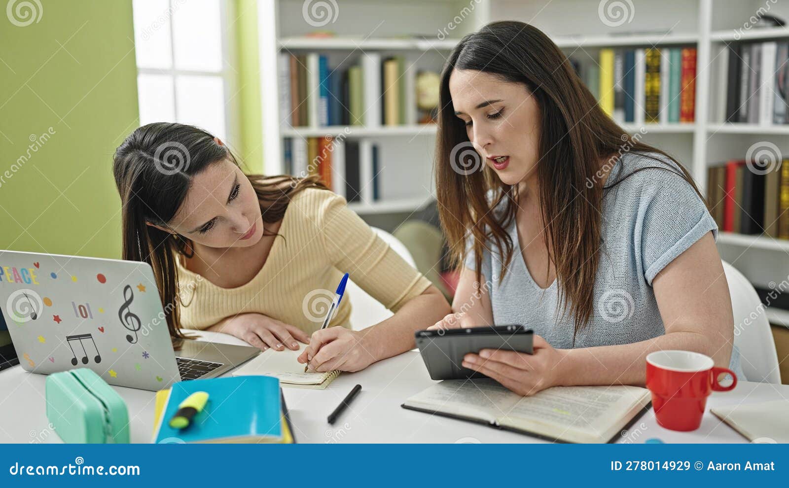 Two Women Sitting on Table Using Touchpad Writing Notes at Library ...