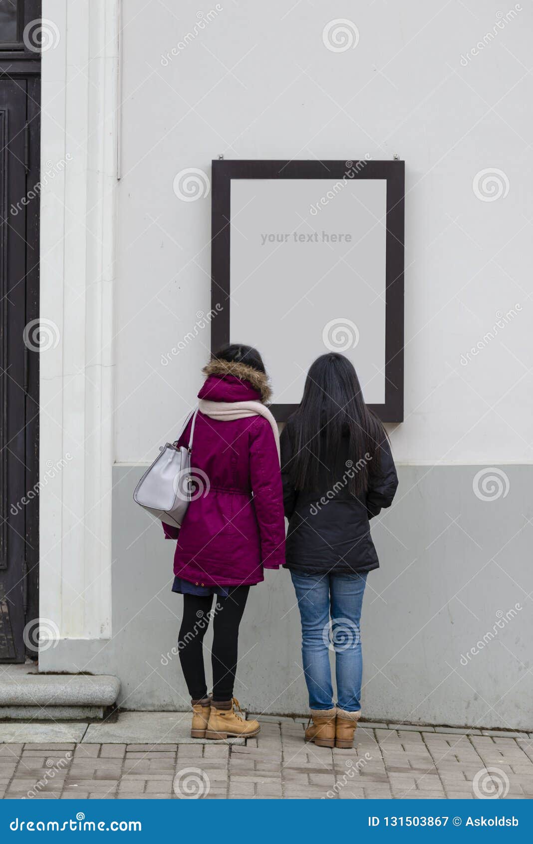 Two Women Stand at the Poster and Read the Text. View from the Back ...