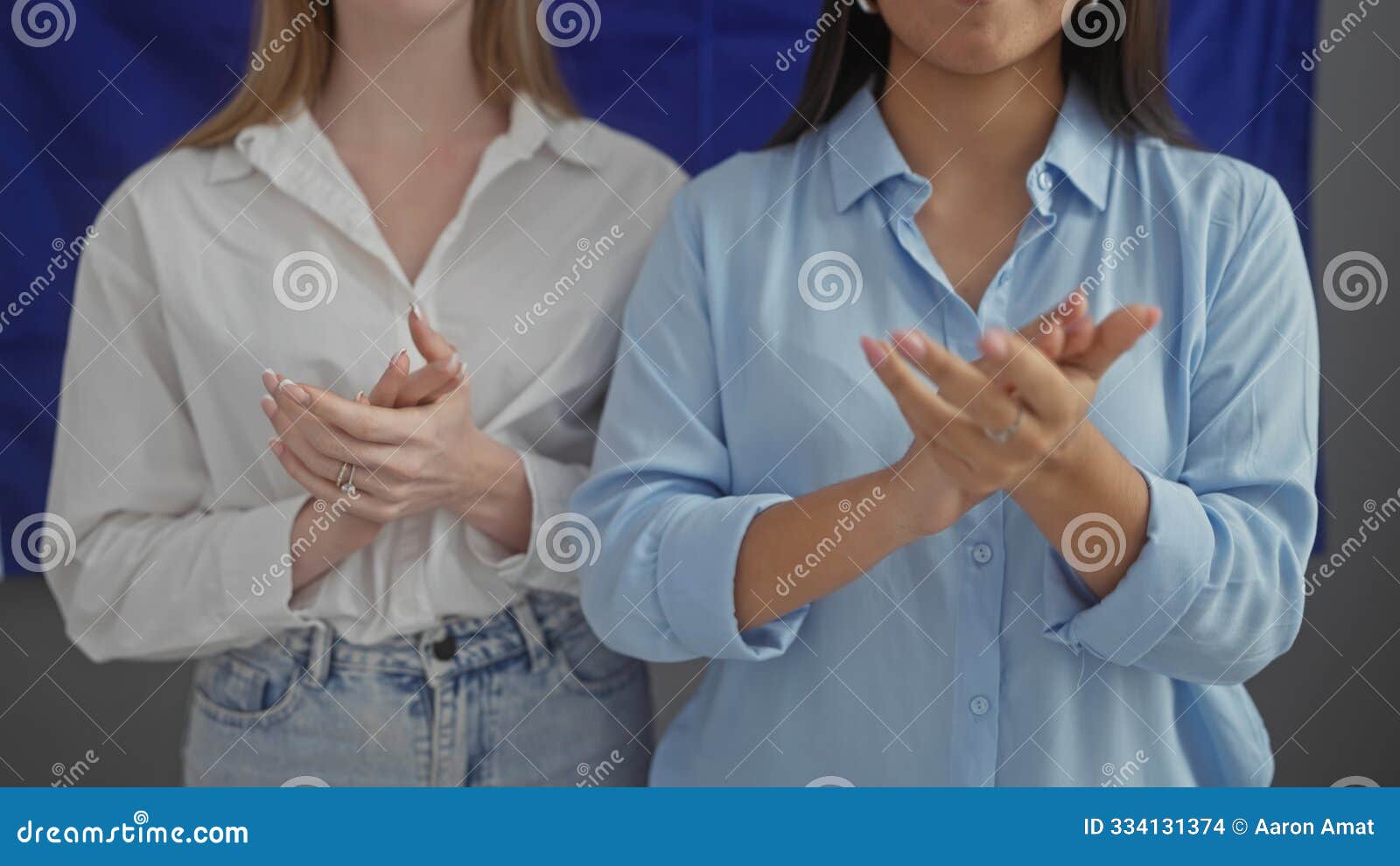 Two Women Standing Together in Front of a Blue Flag, Clapping Indoors ...
