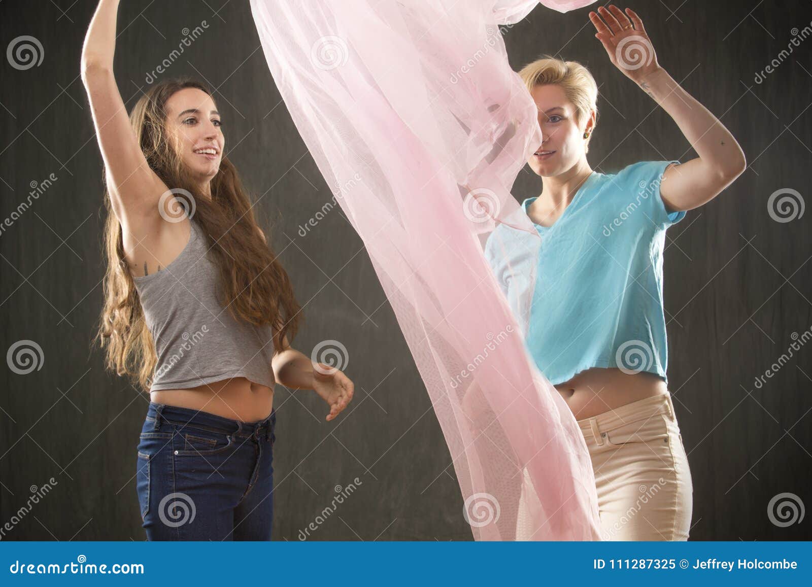 Two Women Tossing Pink Fabric in the Studio. Stock Image - Image of ...