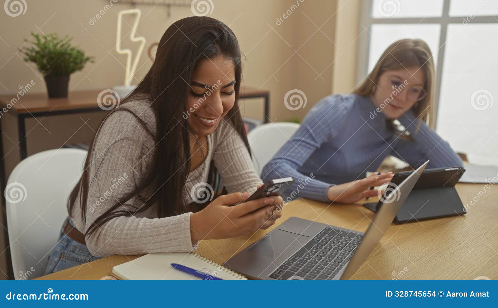 Two Women Using Technology Devices while Sitting Together in a Modern ...