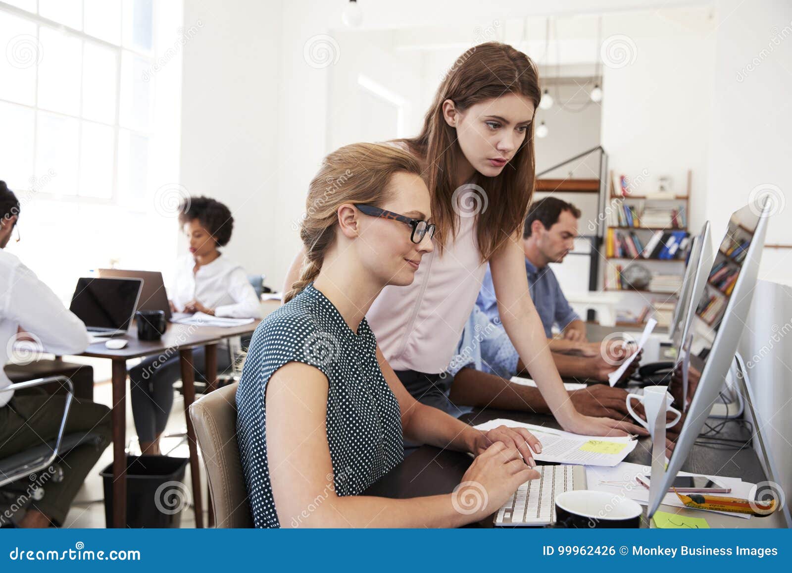 Two Women Working Together at Computer in Open Plan Office Stock Photo ...