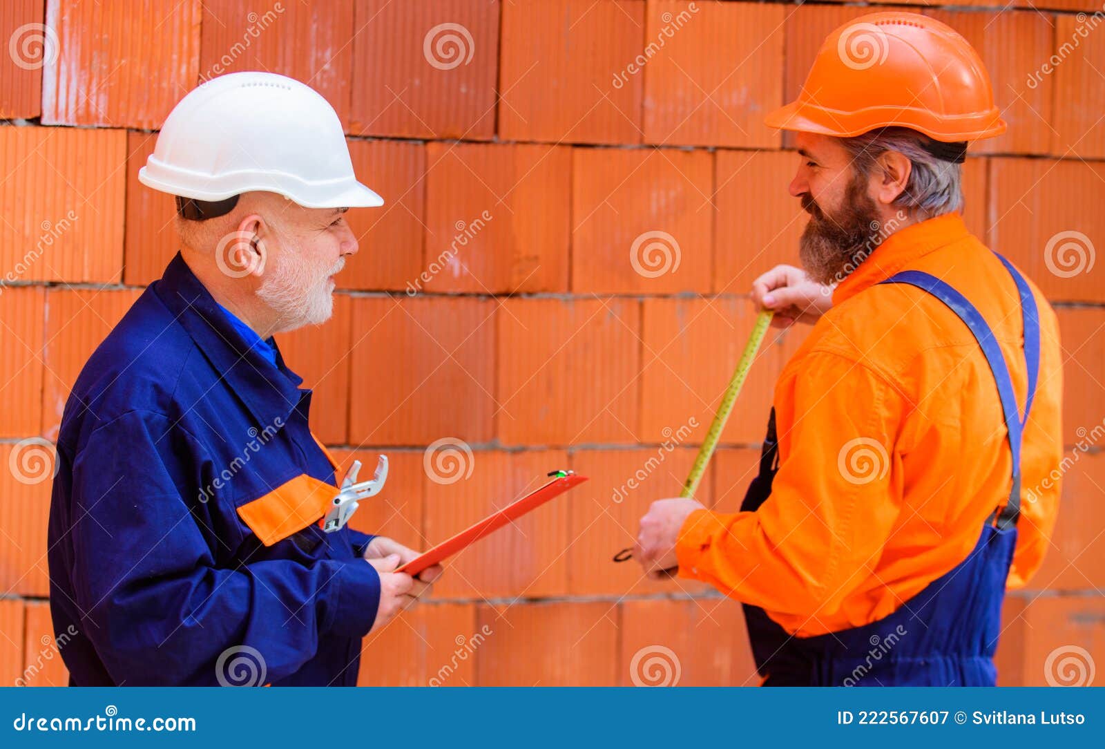 Two Workers with Helmets and Builder Uniform in Construction Site ...