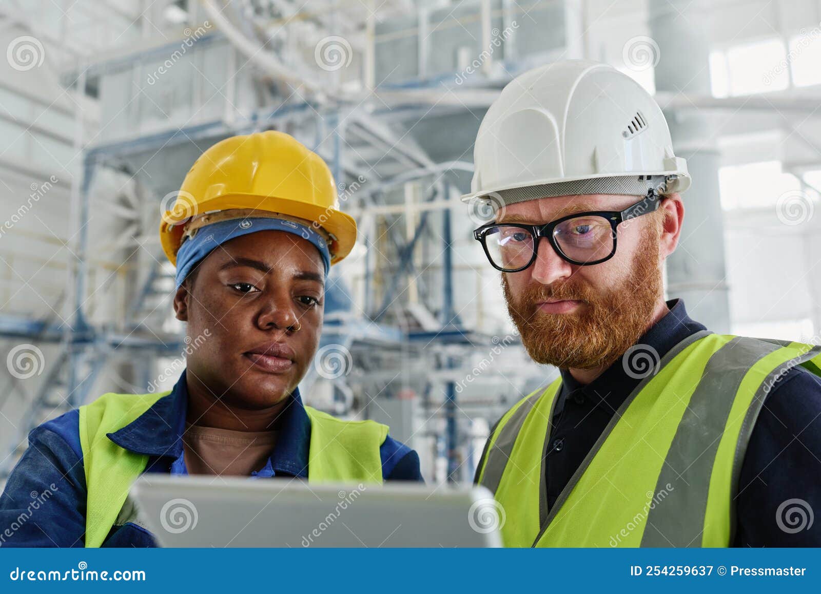 Two Workers of Modern Factory Looking through Information at Tablet ...