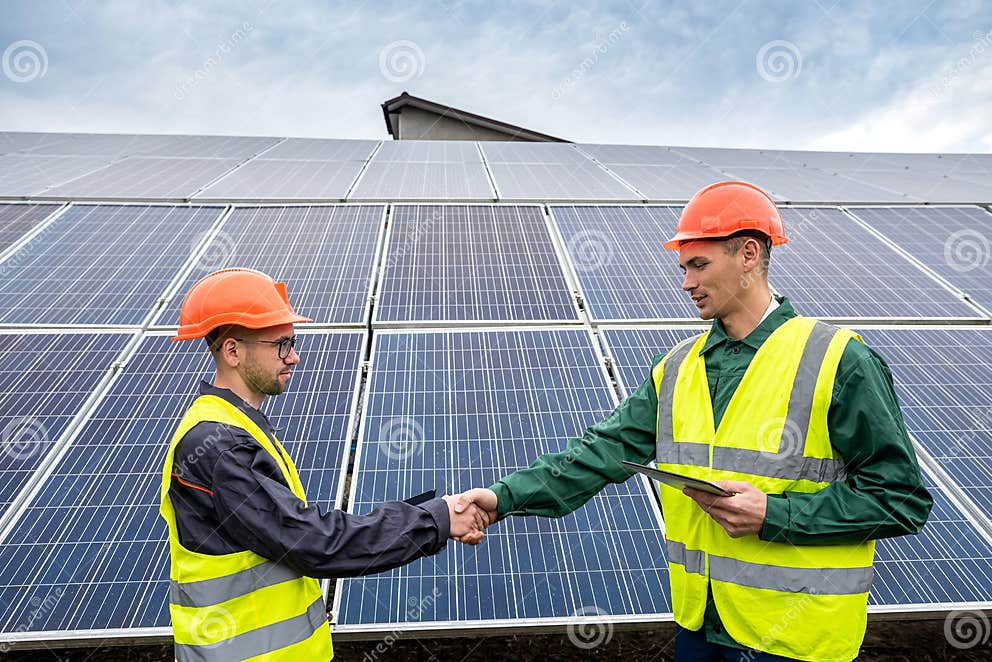 Two Workers in Overalls and Helmets Shake Hands after Completing a ...