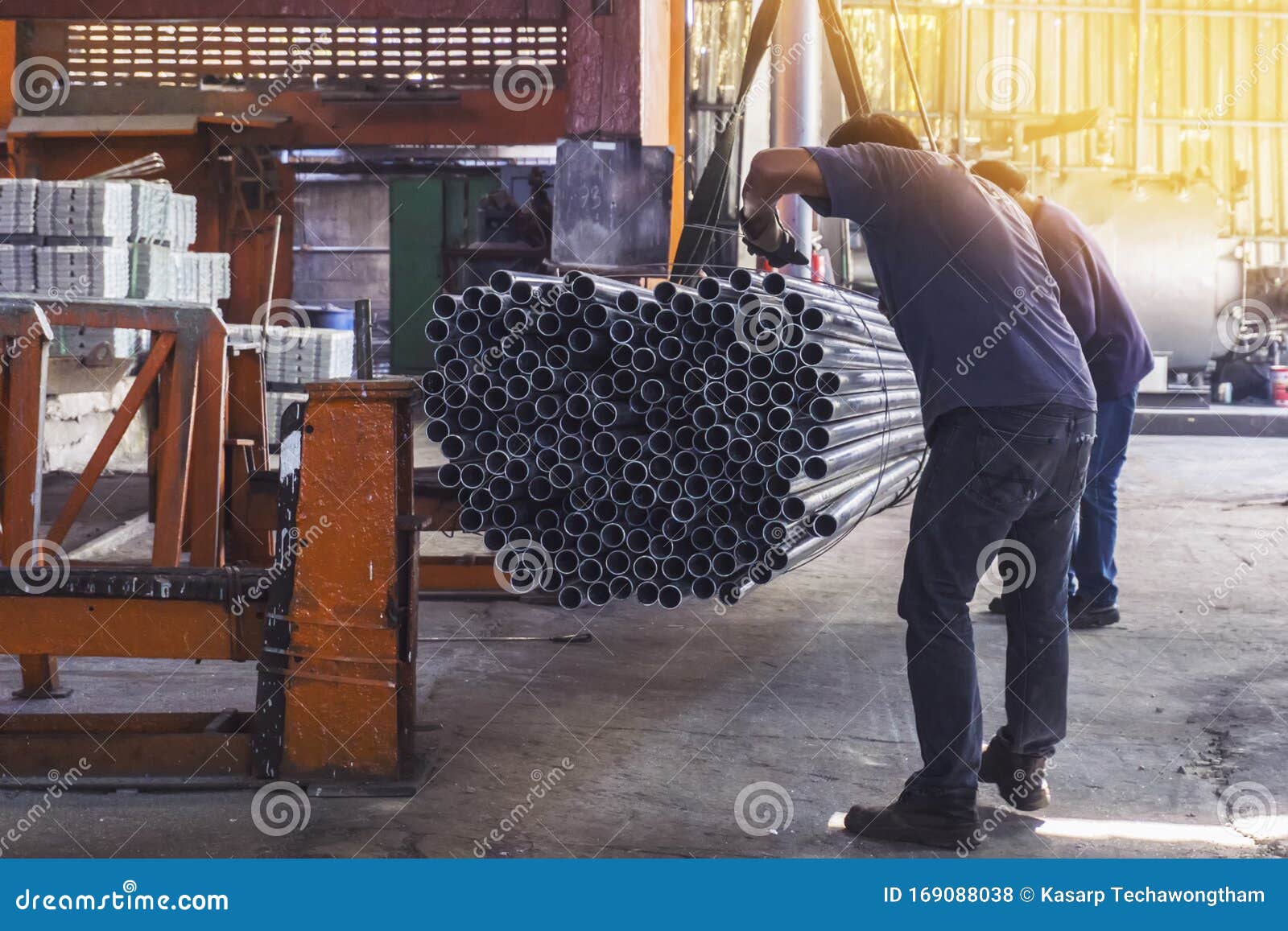 Two Workers in Uniform Using Lifting Machines To Move Metal Pipe in a ...