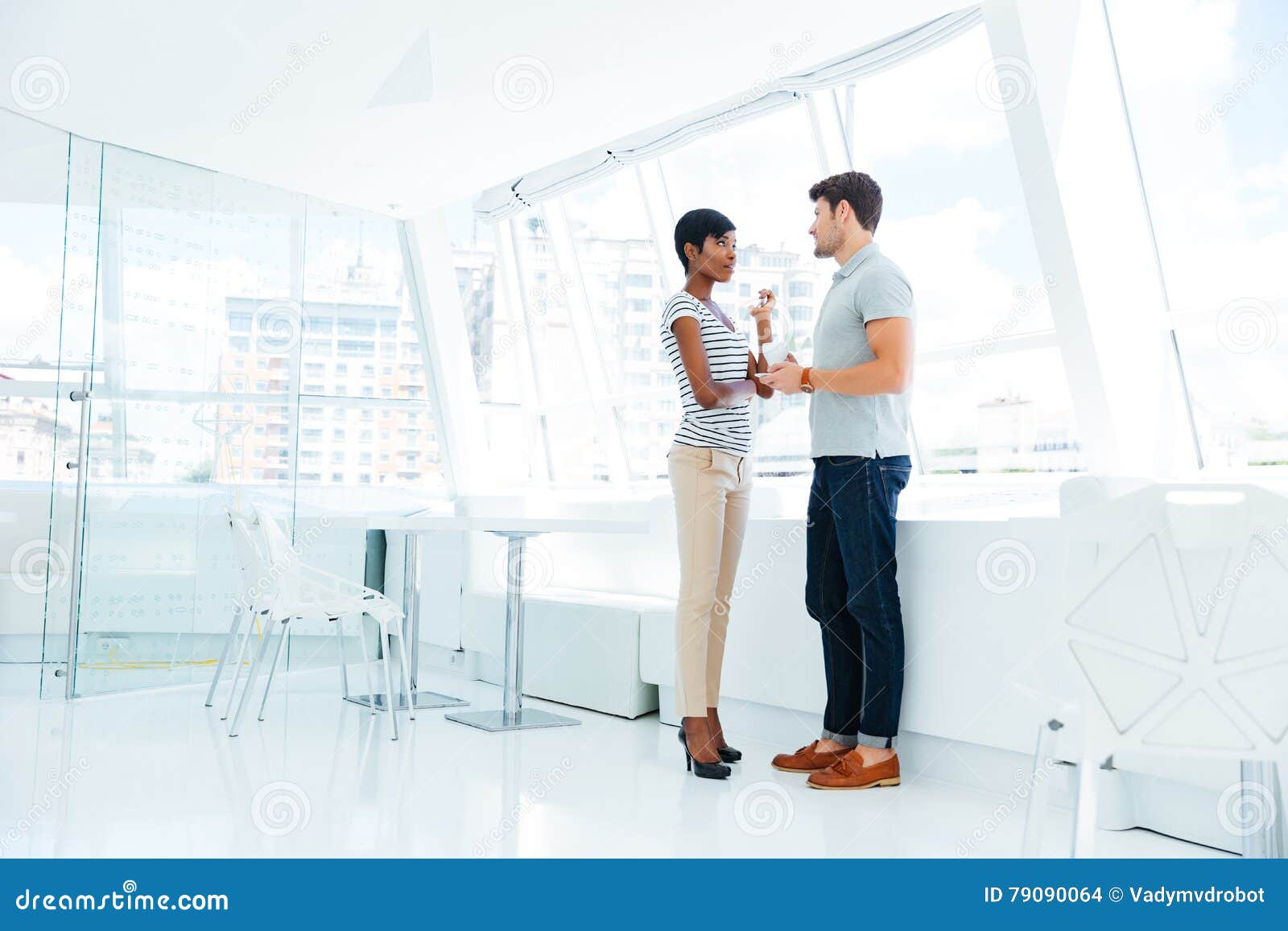 Two Young Business People Standing and Talking in Office Stock Photo ...